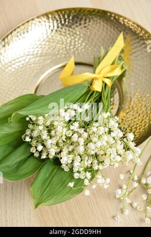 Plate with beautiful lily-of-the-valley flowers on light wooden ...
