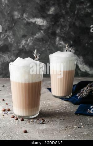 Glasses of tasty lavender latte and flowers on color background Stock ...