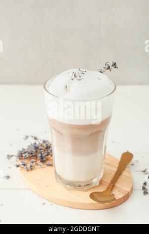 Glass of tasty lavender latte and flowers on color background Stock ...