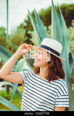 smiling pretty woman in fedora hat sitting in outdoors restaurant ...