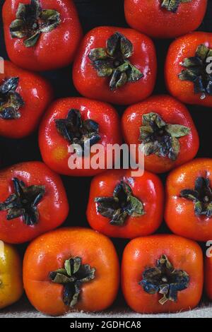 A vertical top view of persimmons on a dark surface Stock Photo - Alamy
