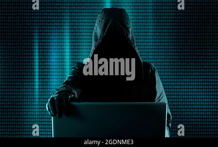 Hacking system, cybercriminal behind a laptop, digital binary code in the background. Hacker ...