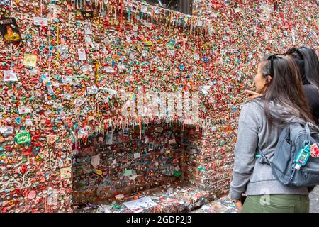 Tourists photograph the Seattle chewing gum wall tourist attraction ...