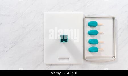 Dipping frozen cakesicles into melted chocolate to prepare mermaid ...