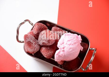 Frozen strawberries in silver bowl on white and red Stock Photo - Alamy