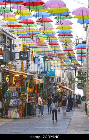Colorful umbrellas hanging over street in idyllic old town with stone ...