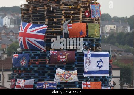 Flags are hung on a large bonfire being built to mark the Catholic ...