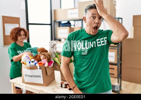 Middle age man wearing volunteer t shirt at donations stand smiling ...