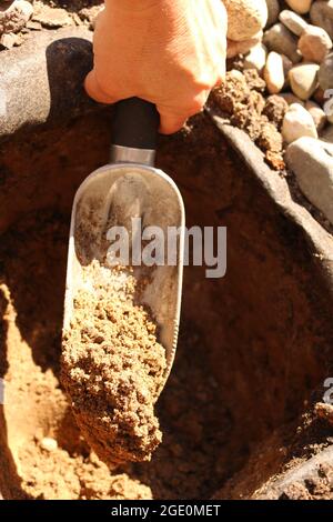 Using a garden trowel to dig a hole Stock Photo - Alamy
