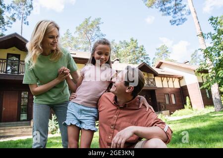 Smiling girl hugging parents on yellow couch Stock Photo - Alamy