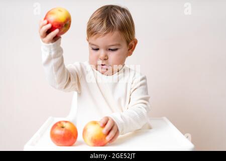 Toddler baby with apples on the high chair. Healthy eating. Summer and ...