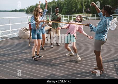 Young man bending backwards to walk under vertical bar in hands of his ...