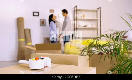 scotch tape on boxes near blurred couple hanging painting in new home ...