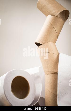 Closeup of unwrapped toilet paper and a stack of empty toilet paper ...
