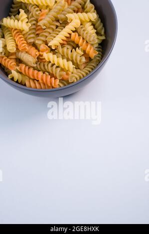 Vertical shot of tri-color rotini and rigatoni pasta on a bowl isolated ...
