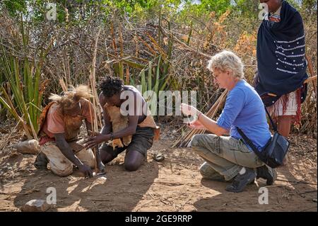 tourist watching bushmen making fire, bushmen of Hadzabe tribe sitting ...