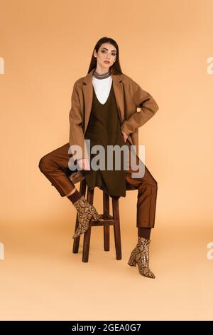 A woman in brown leather coat walking down a rainy city street carrying ...