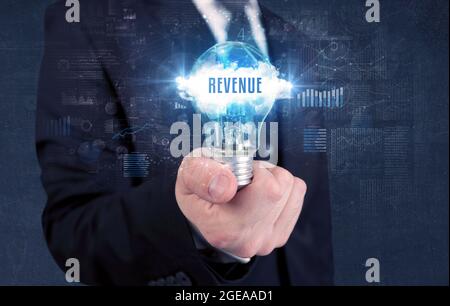 Businessman holding a light bulb with REVENUE inscription, new business ...