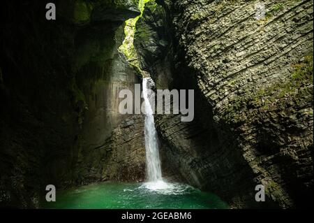 Crystal clear waterfall in a limestone cave flooded with sunlight and ...