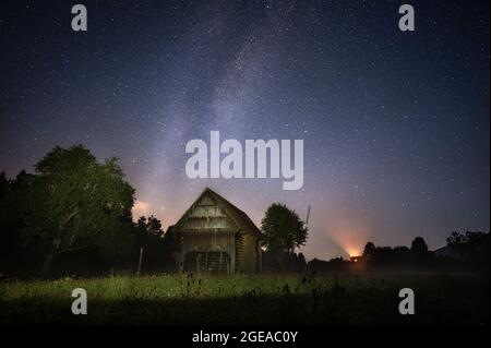 Milky way over traditional Slovenian barn house (hayloft) in the night ...