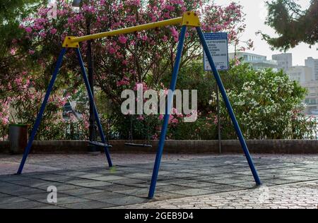 An empty swing set on a chain in an outdoor playground Stock Photo - Alamy