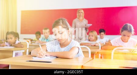 Diligent tween girl studying with classmates in elementary school Stock ...
