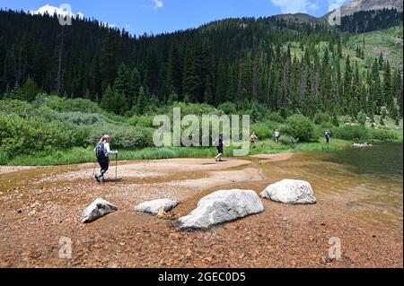 Hikers cross shallow water of Upper Urad Reservoir on Hassell Lake ...