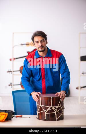 Young repairman repairing musical instruments at workplace Stock Photo ...
