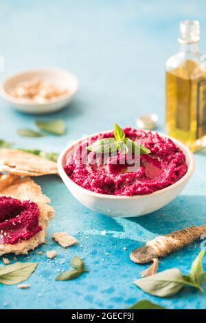 red beetroot hummus on blue background, lemon, sesame, olive oil, pita ...