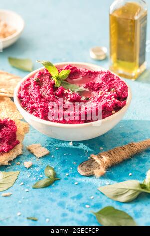 red beetroot hummus on blue background, lemon, sesame, olive oil, pita ...