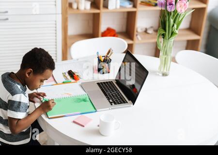 Black boy using laptop and drawing while sitting at home Stock Photo ...