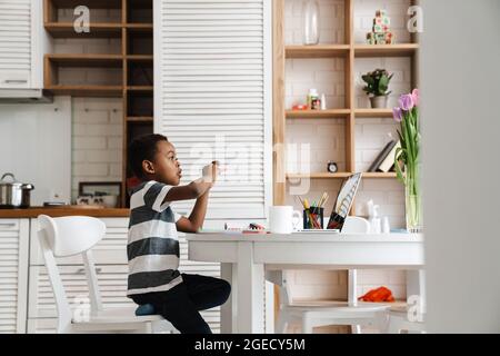 Black boy using laptop and drawing while sitting at home Stock Photo ...
