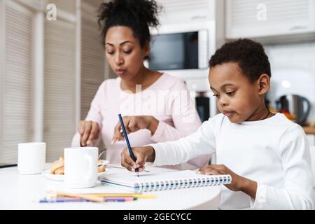 Black boy drawing while having breakfast with her mother at home Stock ...