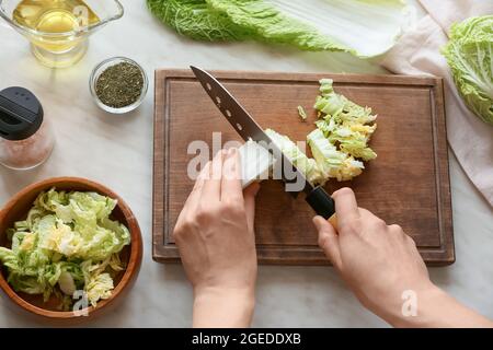 Woman cutting fresh Chinese cabbage at light grey table, closeup Stock ...