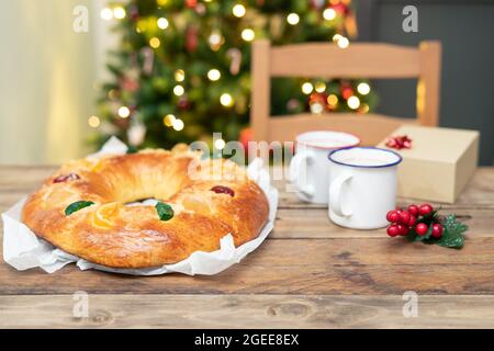 Whole Roscón de Reyes on wooden table with Christmas tree in the ...