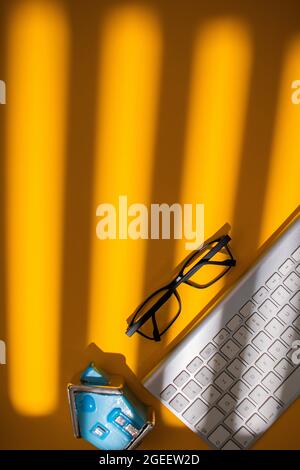 Top view of a vibrant orange shadowy table with a calculator, house toy ...