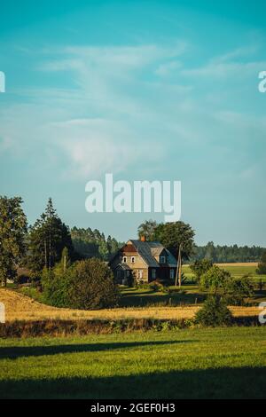 Wooden croft cottage on a grassy field surrounded by trees under a blue ...