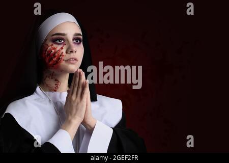 Nun with bloody scars on her face against dark background. Halloween ...