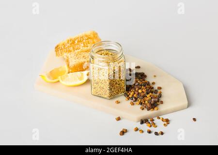 Jar with bee pollen, beebread, honeycombs and lemon on light background ...