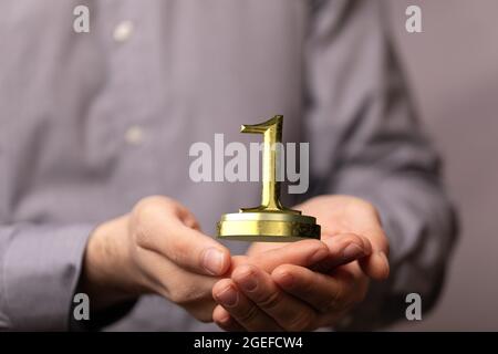 Hand holding a 3D decorative 1st place trophy sign Stock Photo - Alamy