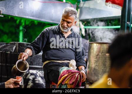 A Kashmiri Shia Muslim man distributes water among Shia mourners during ...