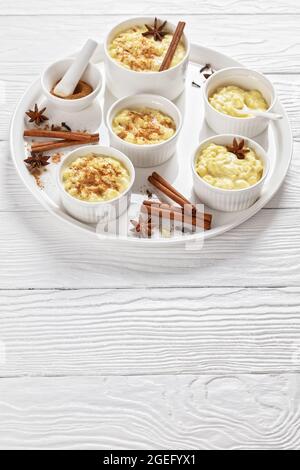 Ceramic bowls of rice pudding and cinnamon with decoration on wooden ...