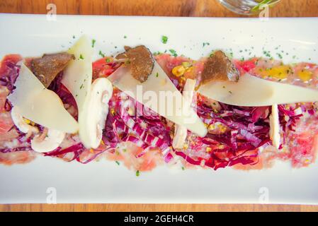Tuna carpaccio with purple cabbage and sliced parmesan cheese on a ...