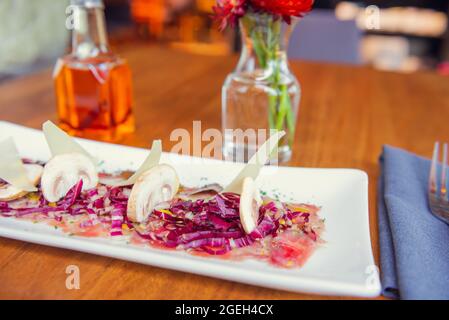 Tuna carpaccio with purple cabbage and sliced parmesan cheese on a ...