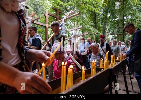 Believers light candles as others walk past with crosses and religious ...
