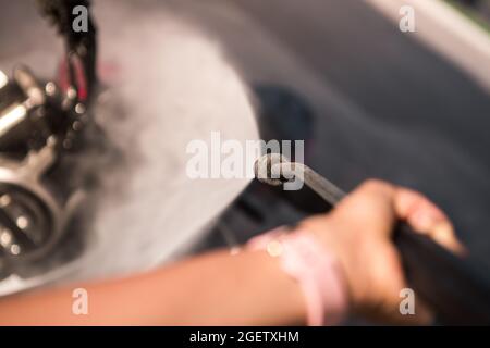 Closeup of a person washing a motorcycle with a water spray gun ...