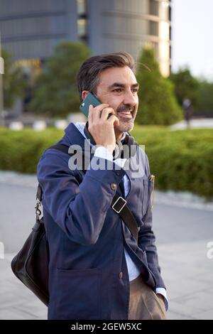 Middle age grey-haired man smiling confident using smartphone at street ...