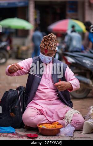 A priest arranging a sacred colorful thread during the festival at the ...