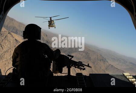 A gunner in a U.S. Army CH-47 Chinook helicopter mans a .50-caliber ...