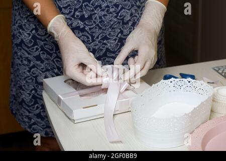 A woman is packing marshmallows in craft packaging. He cauterizes the ...